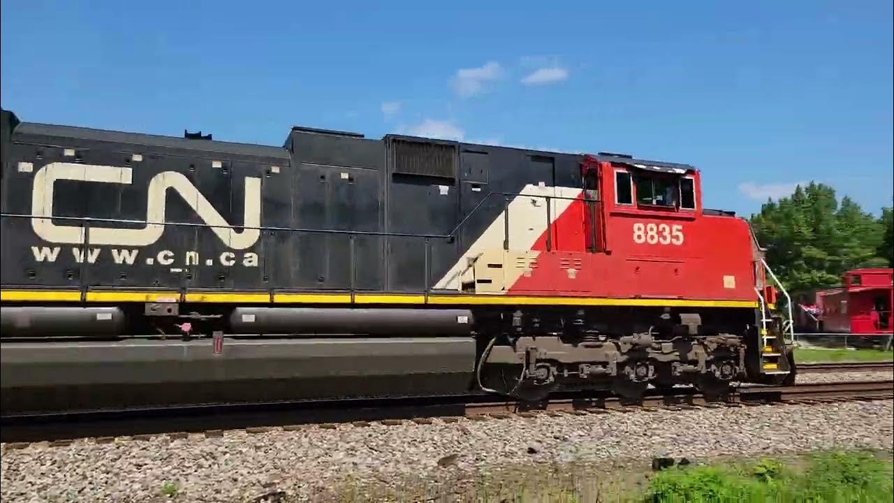 CN 8835 heading Eastbound with a local train of centerbeam flat cars, hoppers, at Vicksburg, MI ...