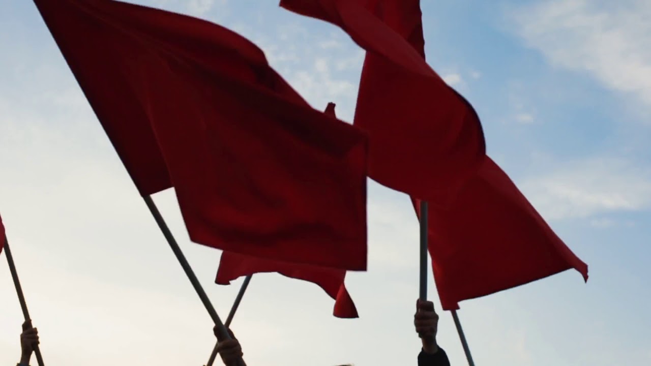 hands of a group of people waving red flags against blue sky - YouTube