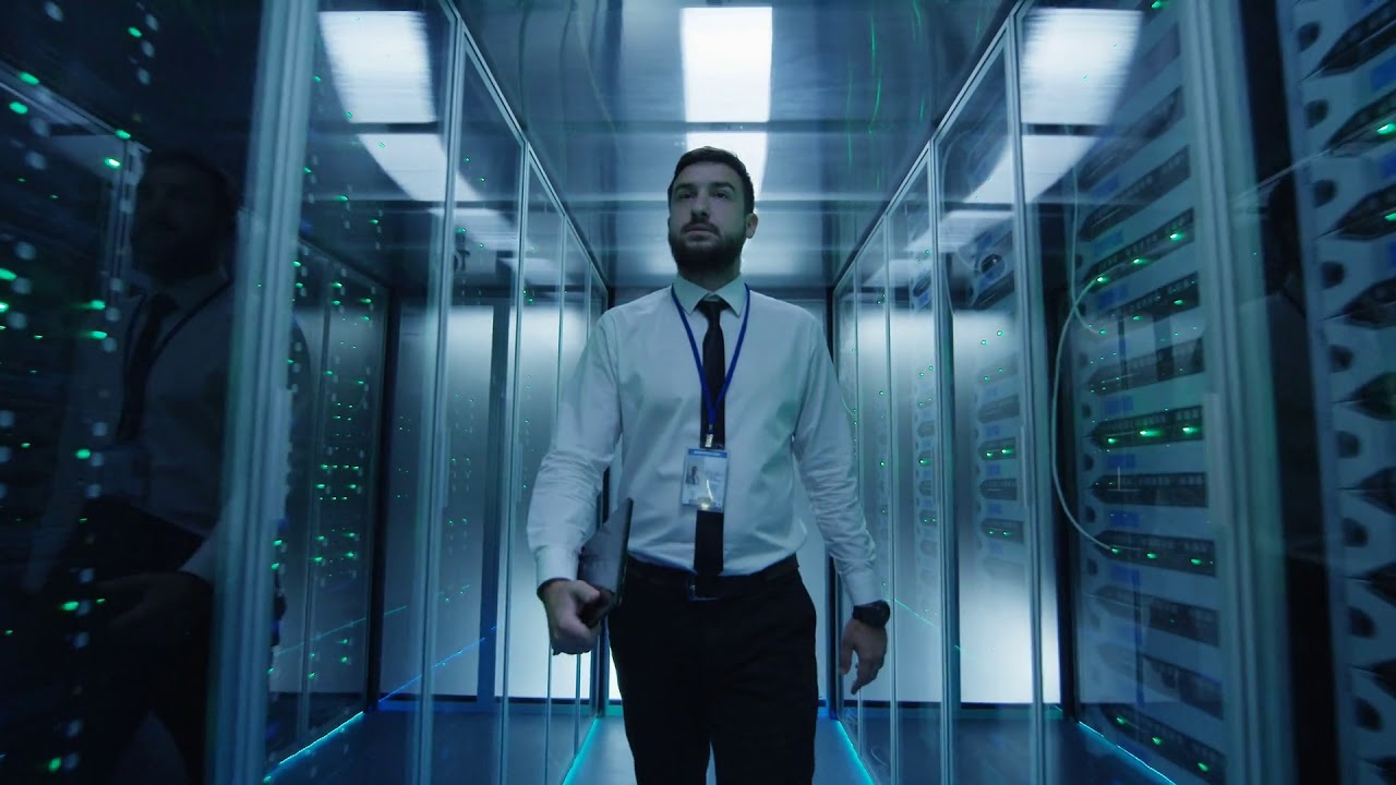 formal man working in data center and walking in corridor with server ...