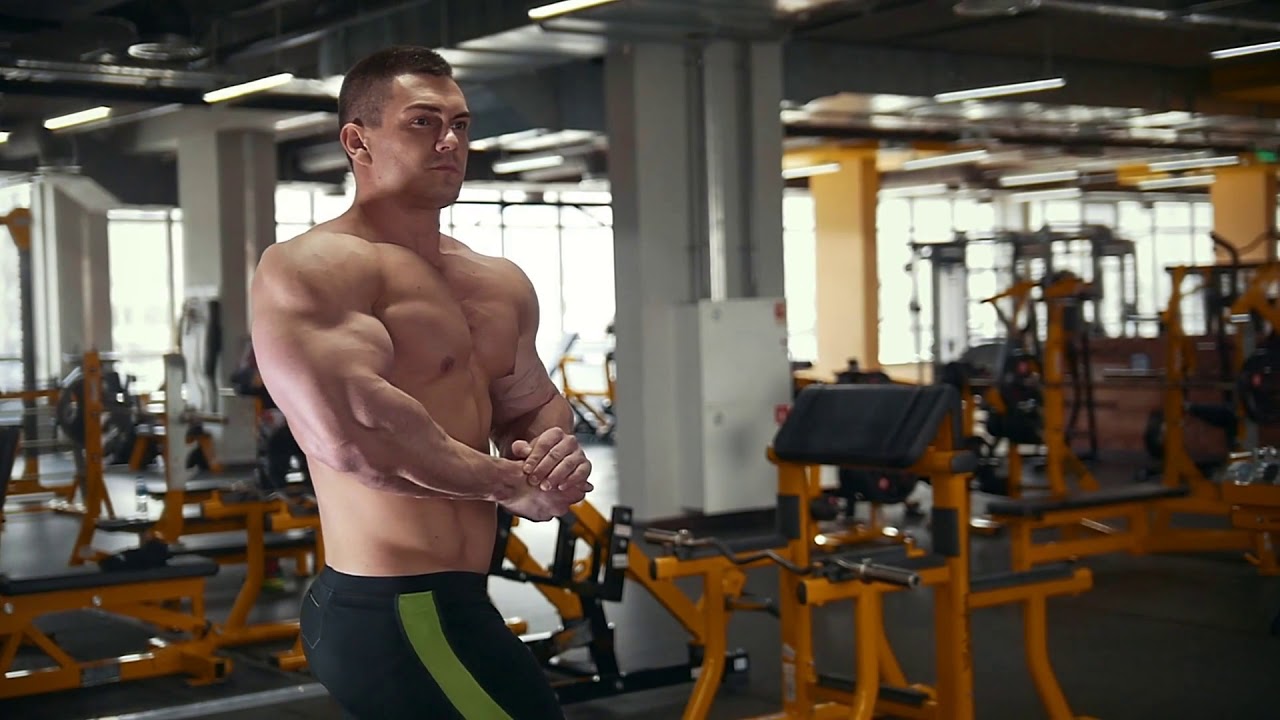 athletic man bodybuilder posing and shows muscles near mirror in the ...