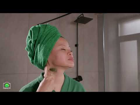 Charming mature Asian woman doing facial massage using jade roller in bathroom