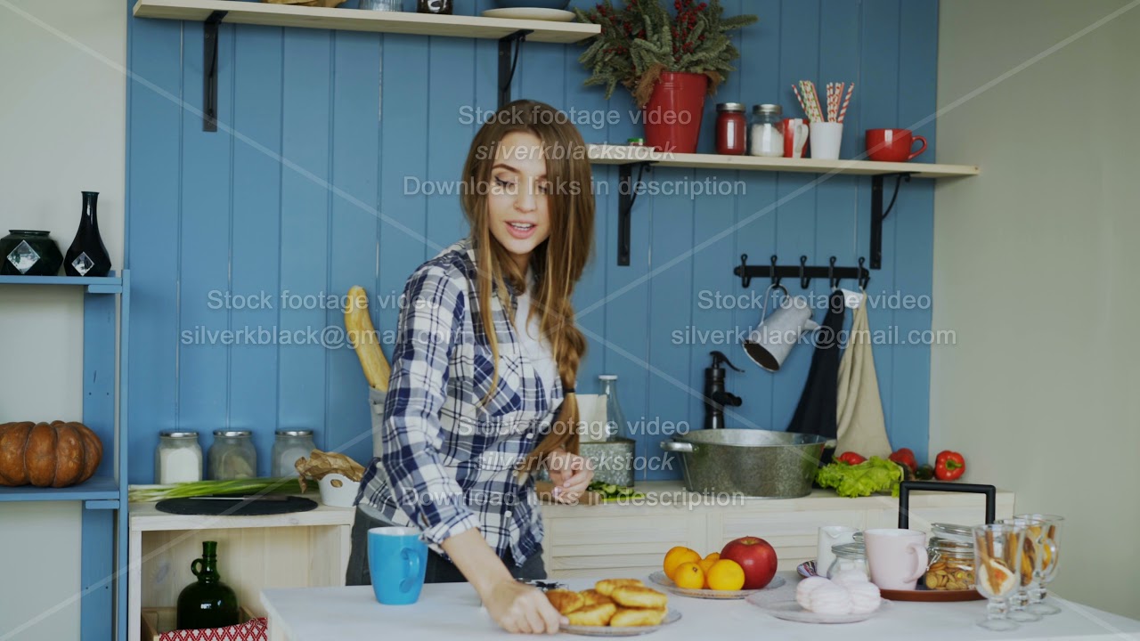 Cheerful young funny woman dancing and singing while cooking breakfast ...