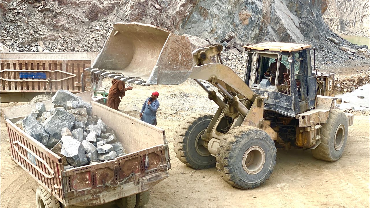 Heavy-Duty Catterpillar wheel loader loading Rocks into trolleys ...