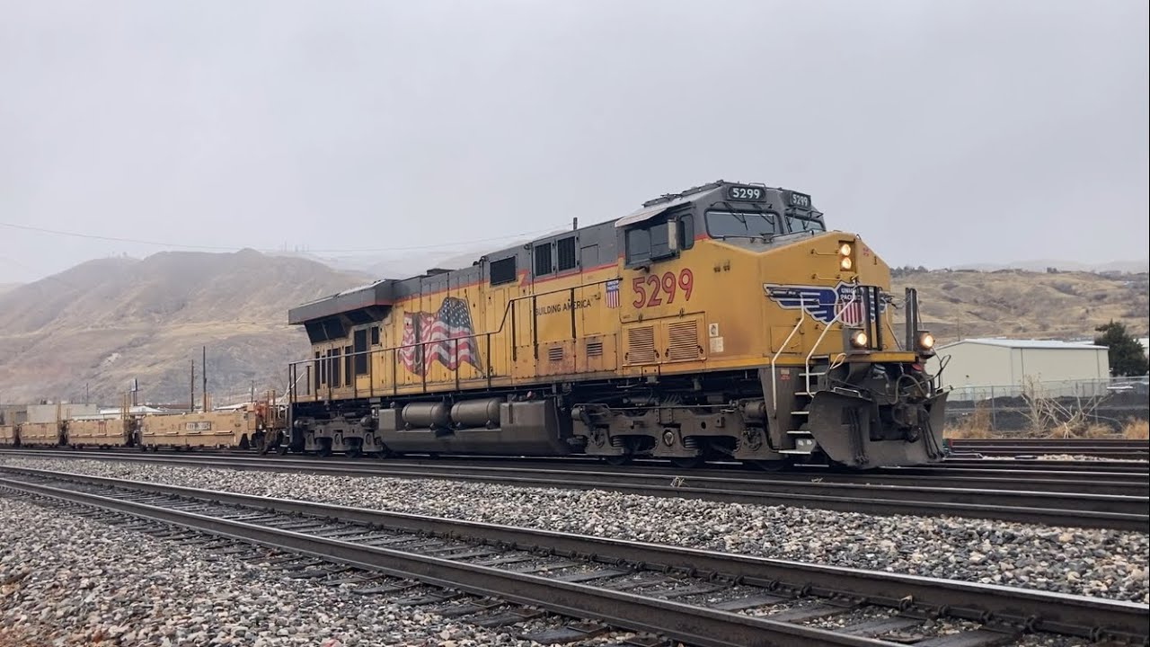 A slow moving UP empty well car train departs SLC, UT with several ...