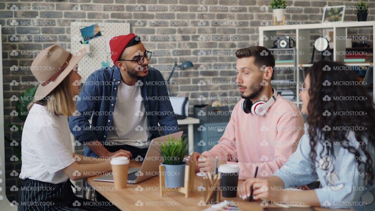 Creative team of designers speaking in office around table ...