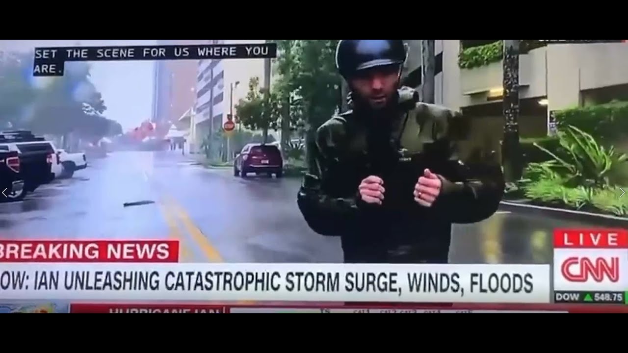 Man casually walking to his car in the background of hurricane Ian ...