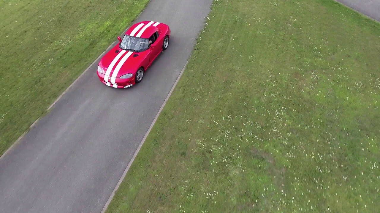 red dodge viper car with white straps on a race circuit aerial drone ...