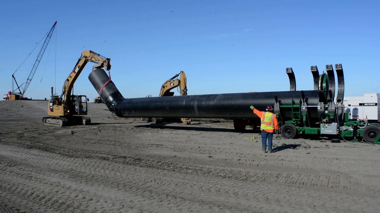 Two excavators and a forklift removing 63" SDR17 HDPE pipe pup from a ...