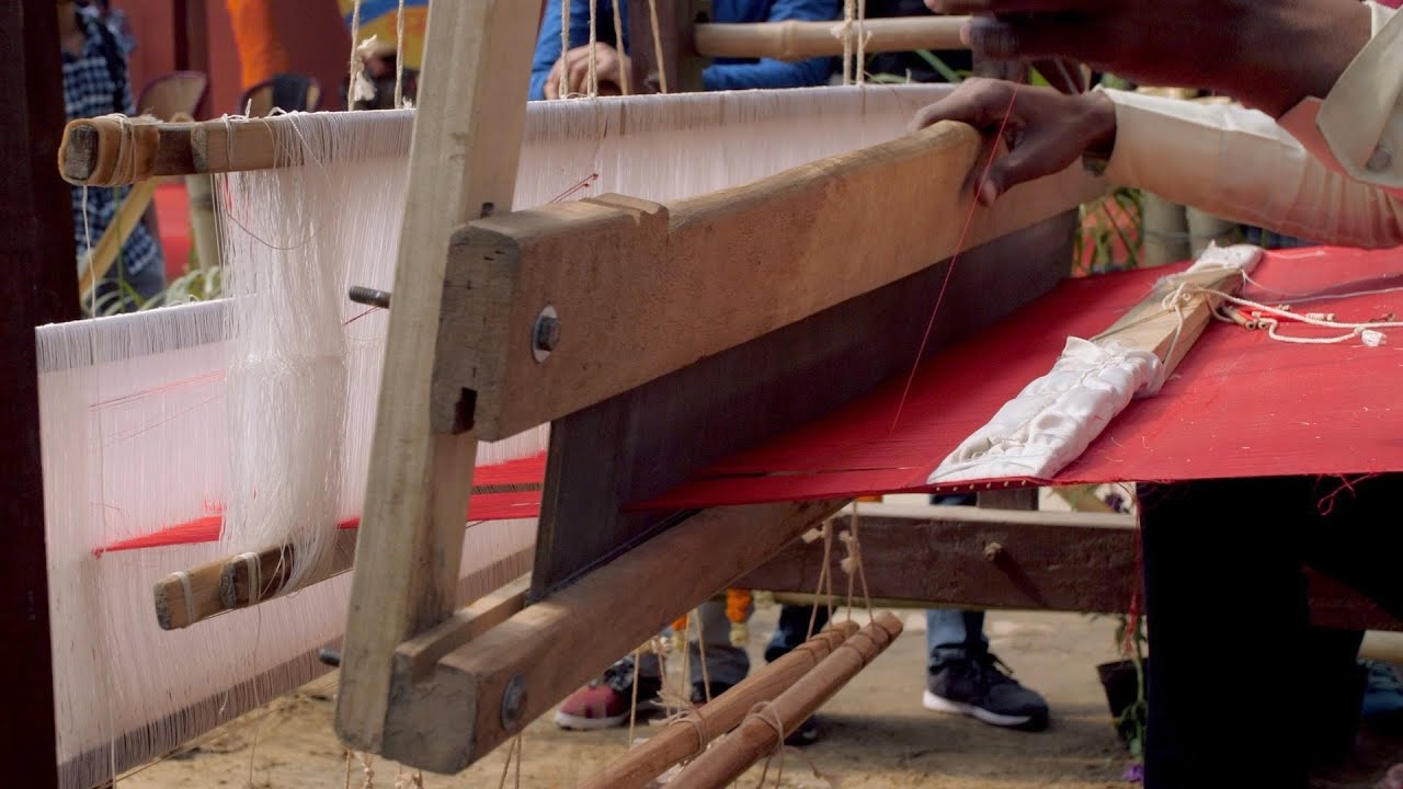 An Indian handloom weaver using weaving machine to make a cloth ...