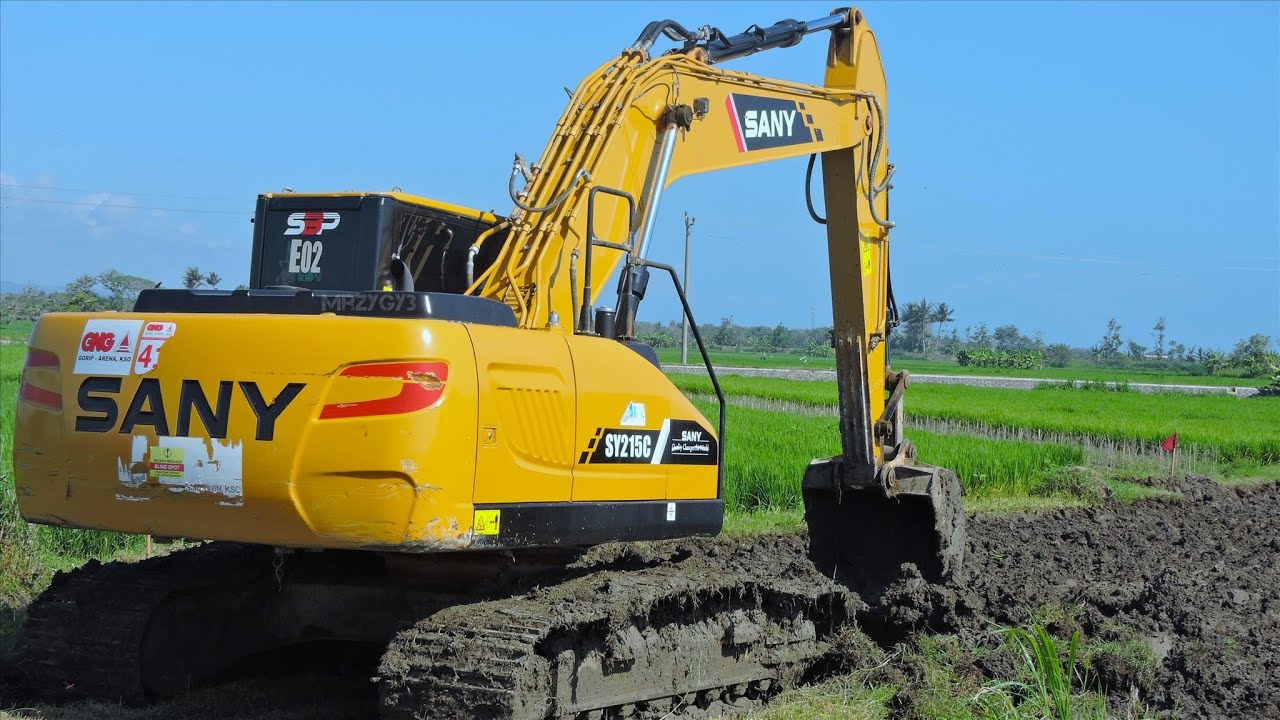 Excavator Working On The Rice Farm Field Digging The Top Soil For The ...