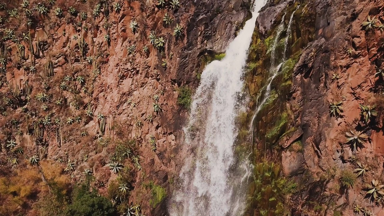 Waterfall over red rocks creating a rainbow (Beautiful world) - YouTube