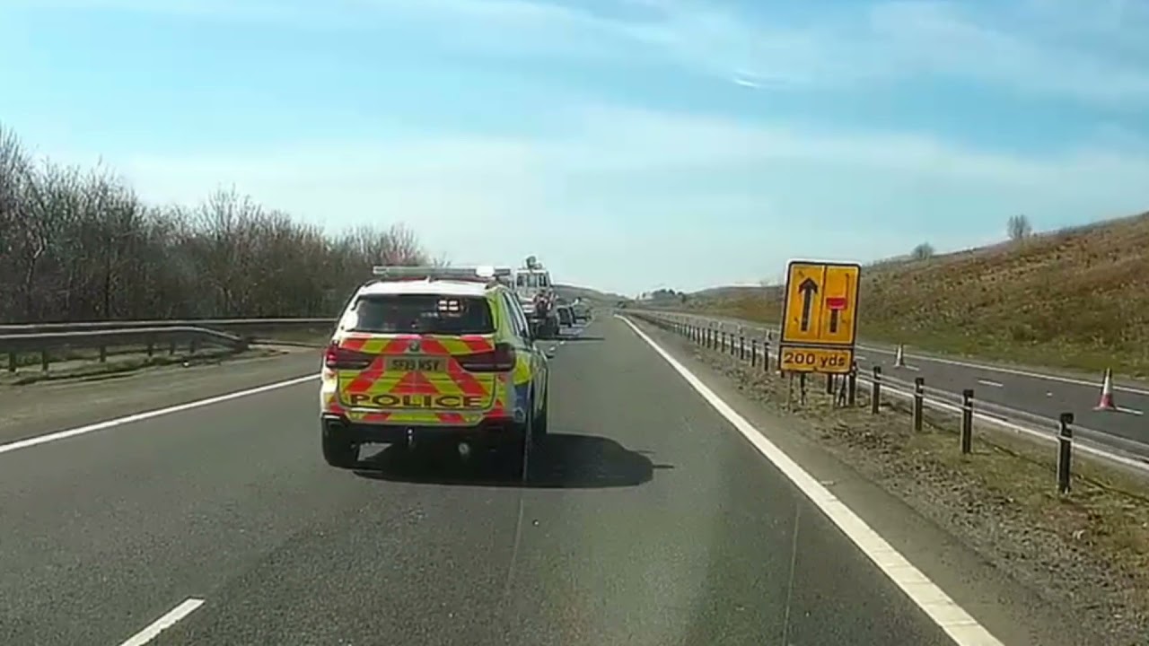Police car straddles lane preventing motorist merging at road works ...