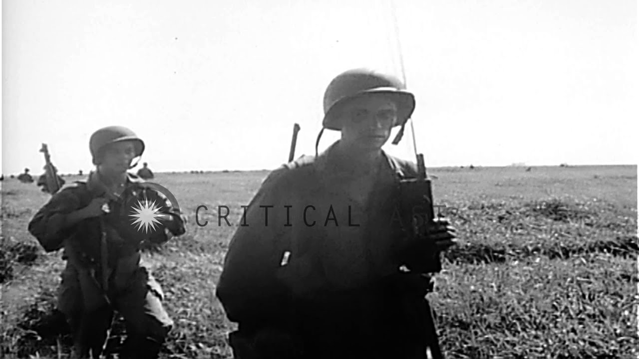 United States 11th Airborne Div. paratroopers advance across a field ...