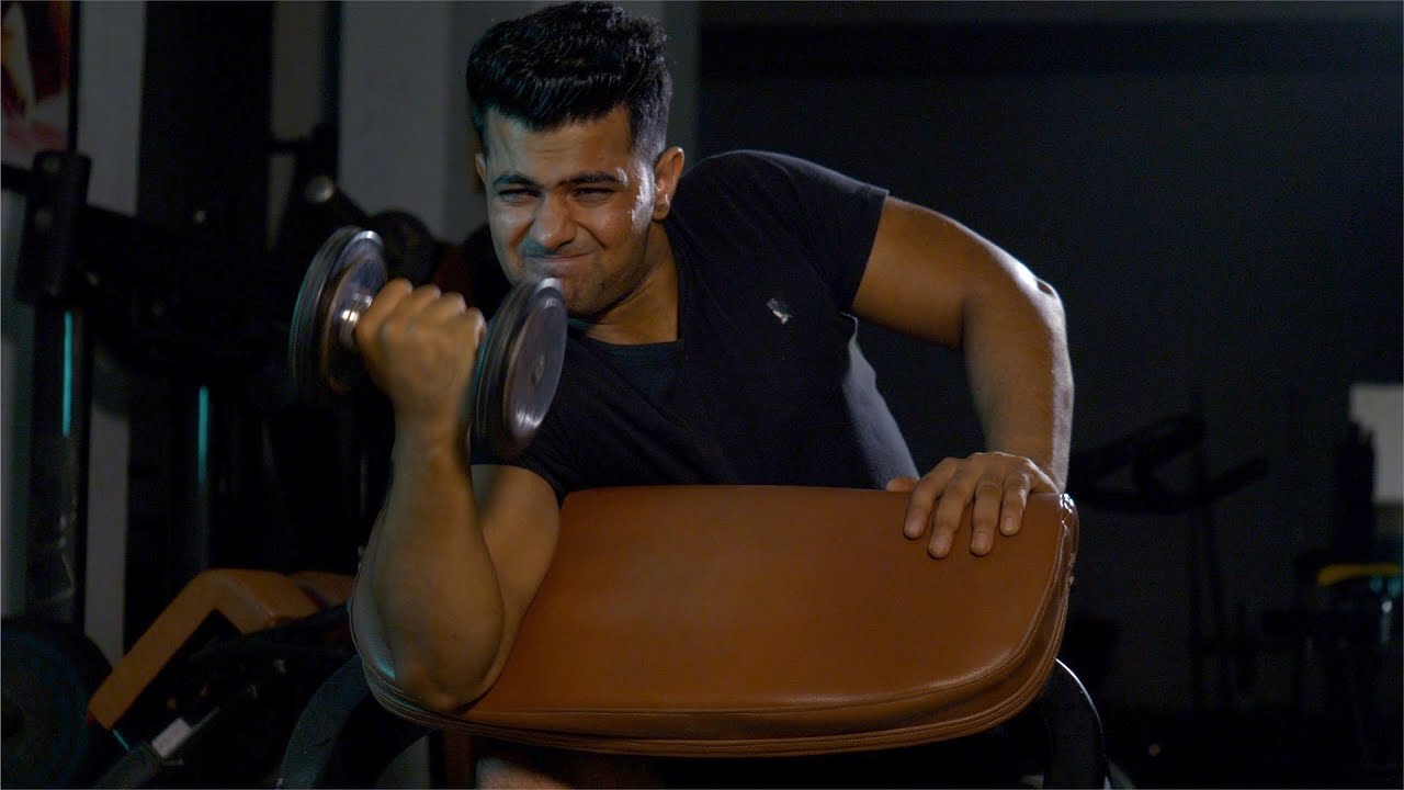 Muscular Indian man doing bicep exercises with dumbbells in a gym ...