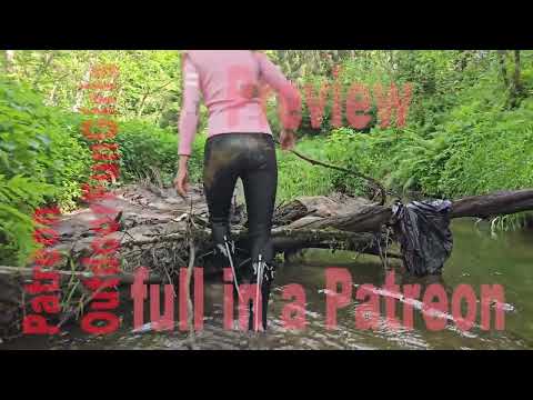 A girl in neoprene pants and a jacket plays in the mud