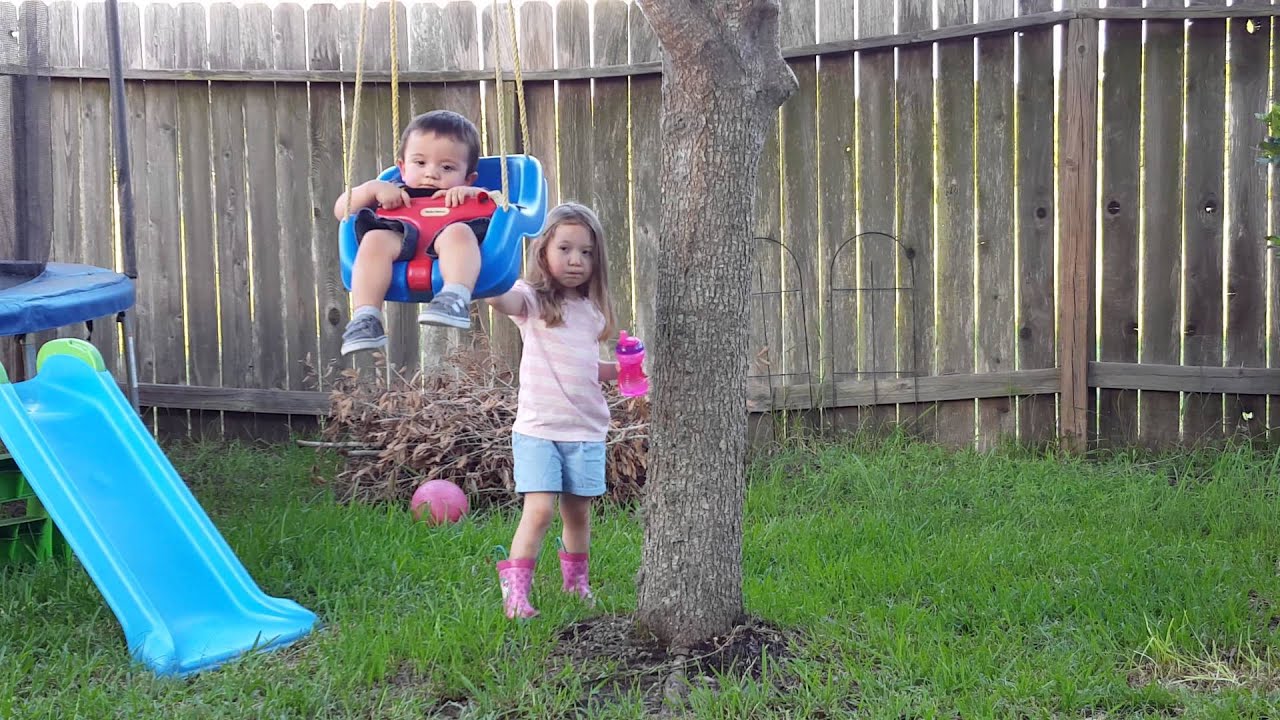 Big sister pushes little brother on the swing - YouTube