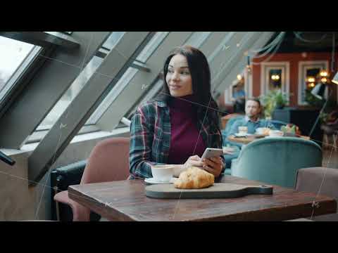 Slow motion of cheerful girl using smartphone and smiling sitting at table in cafe