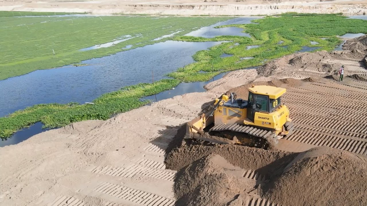 Bulldozer and Dump trucks process pushing sand dumping to filling up ...