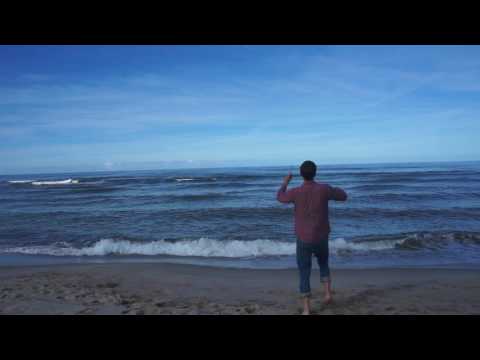 Reurning 3-winged wooden boomerang. Throwing a boomerang to the sea.