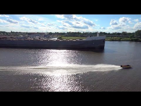 Race boat driver pulls stunt around river freighter