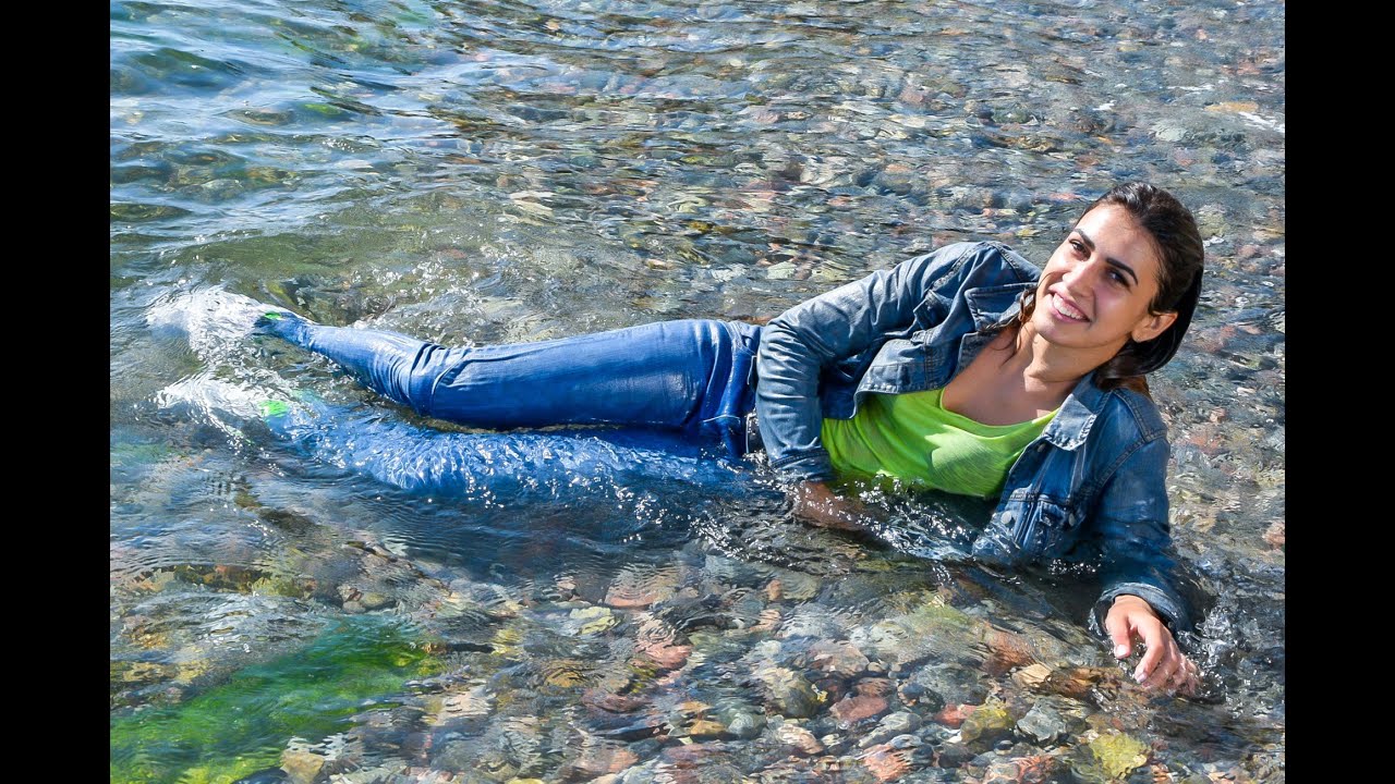girl in wet jeans and a wet denim jacket posing on the beach by the sea ...
