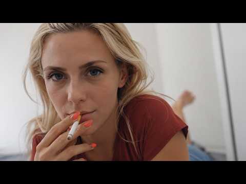 blond woman smoking on bed