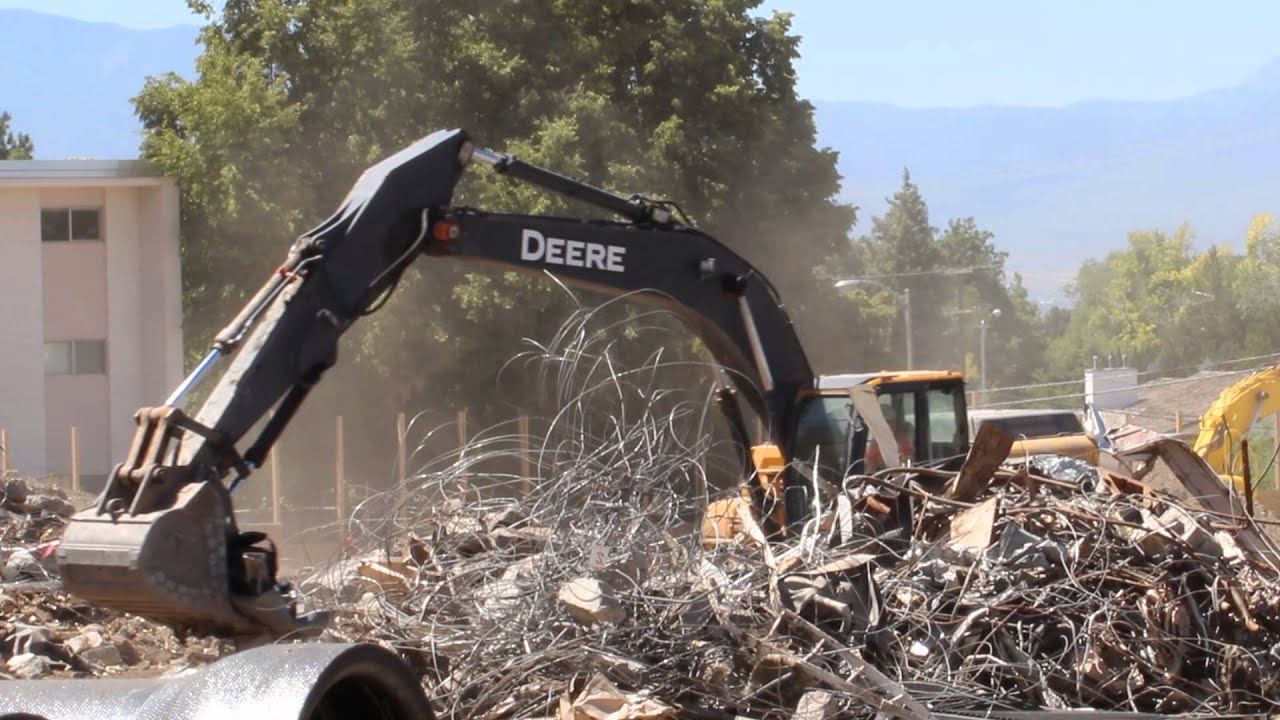 Deere 270D Excavator moves rubble and debris from a torn down building ...