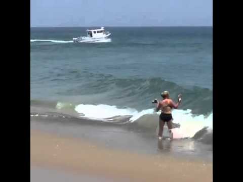 Lady gets knocked down by wave - YouTube