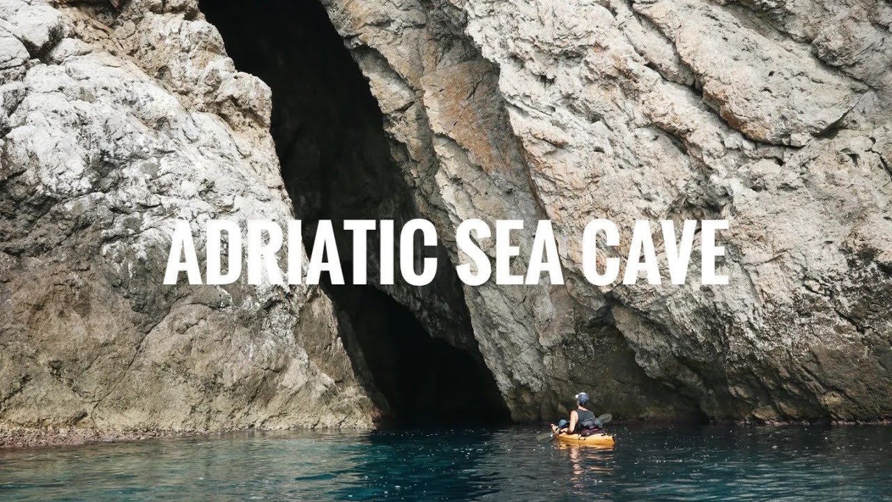 Sea Kayaking: Paddling into a long dark sea cave near Vis island in the ...