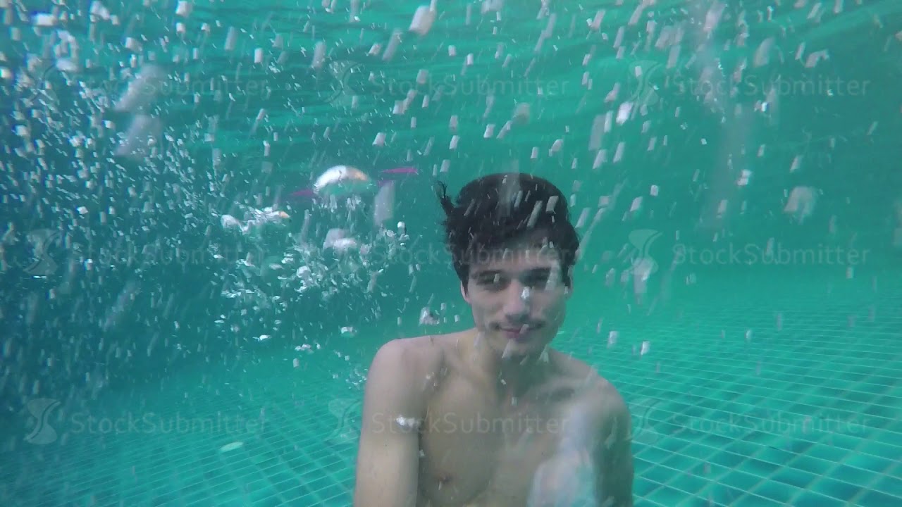 Young man swimming underwater waterdrops falling and splashing in ...