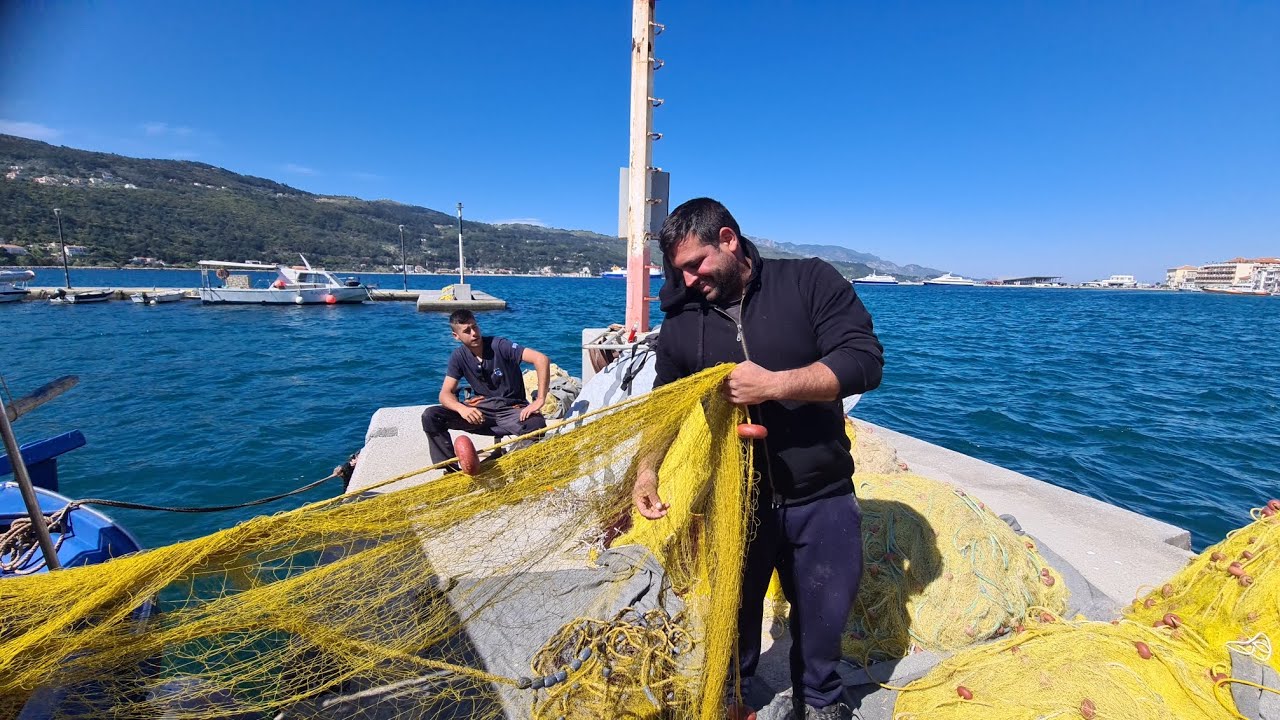 Αλιείς να καθαρίζουν τα δίχτυα αλιείας τους σε τοπική μαρίνα αλιείας ...