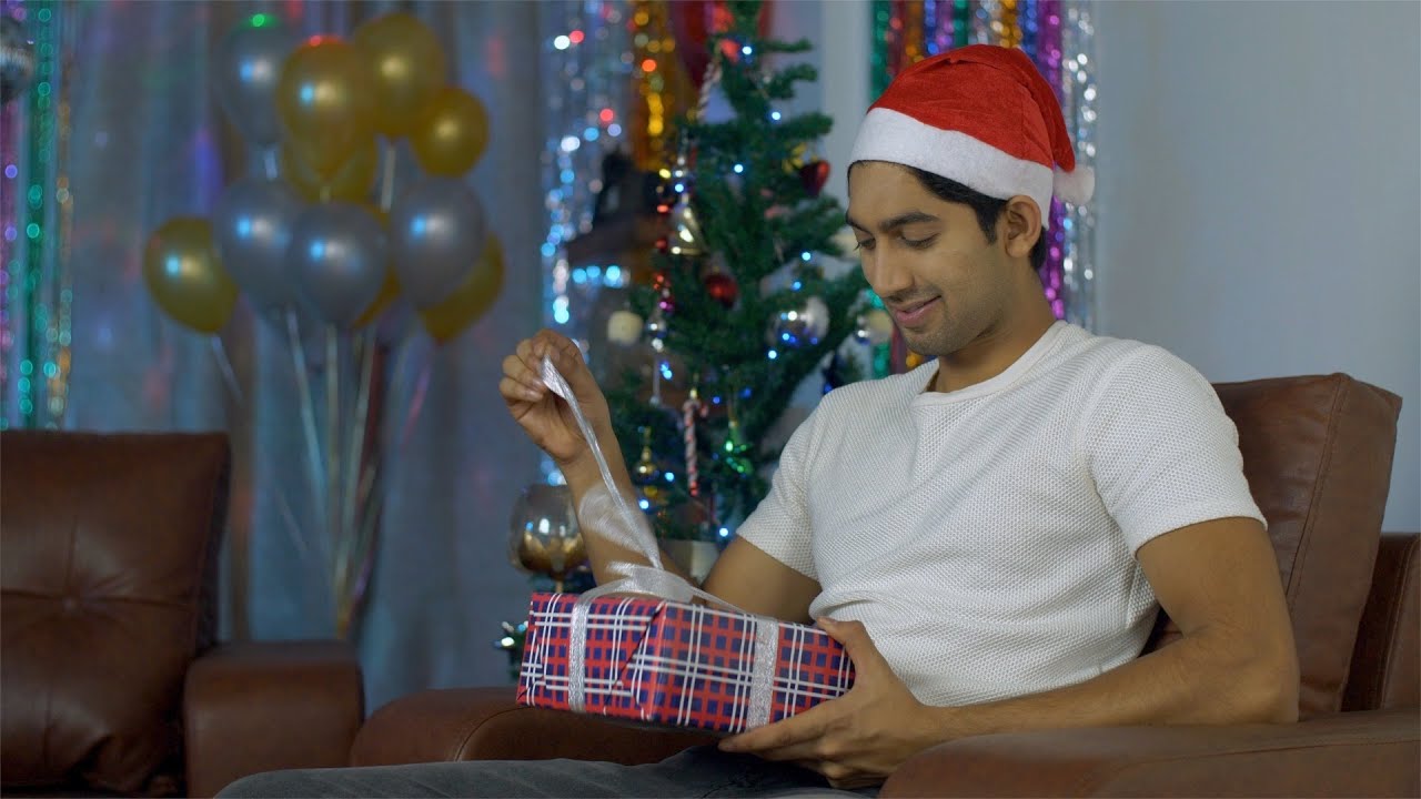 Excited young man opening his colorful Christmas present - fes ...