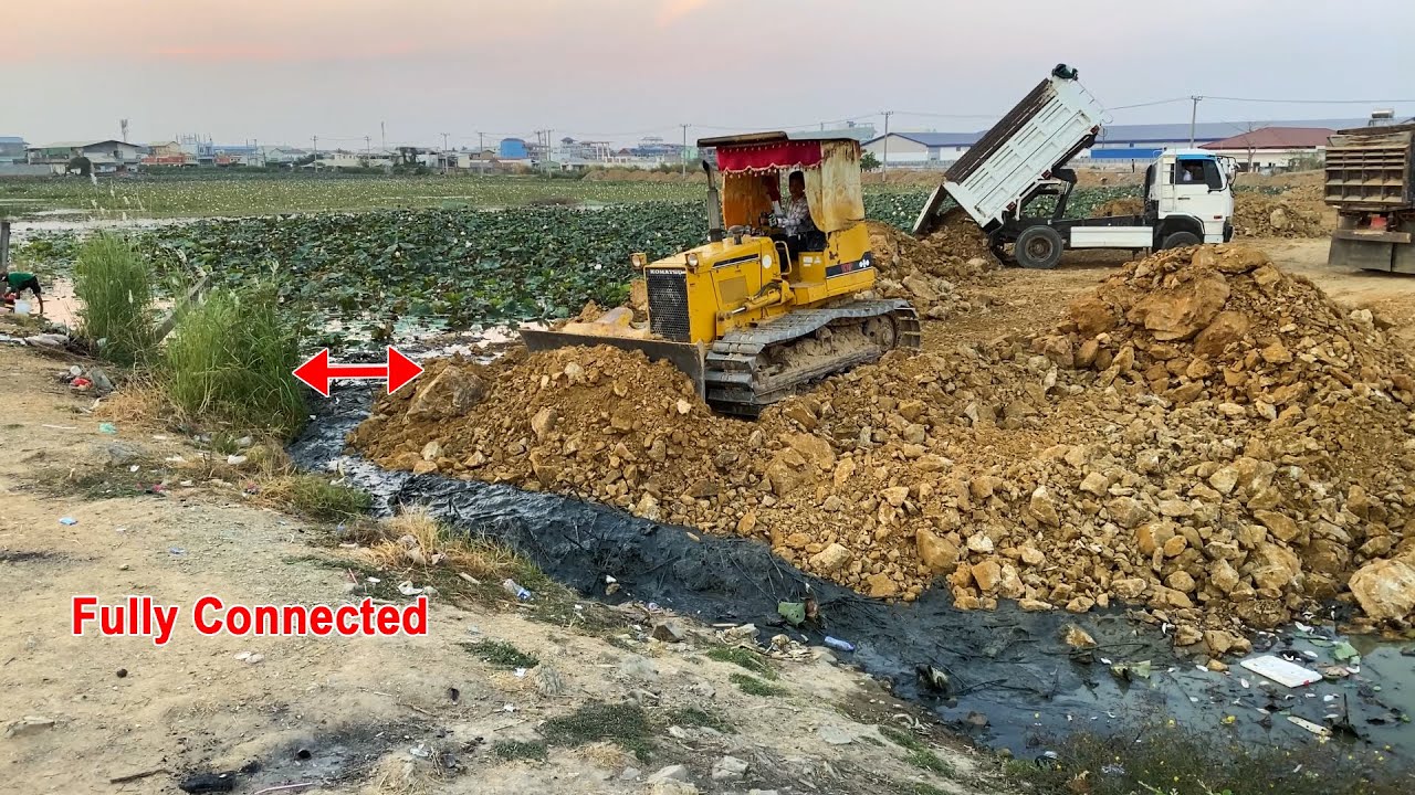 Nice connection border bulldozer filling land over the swamp and water ...