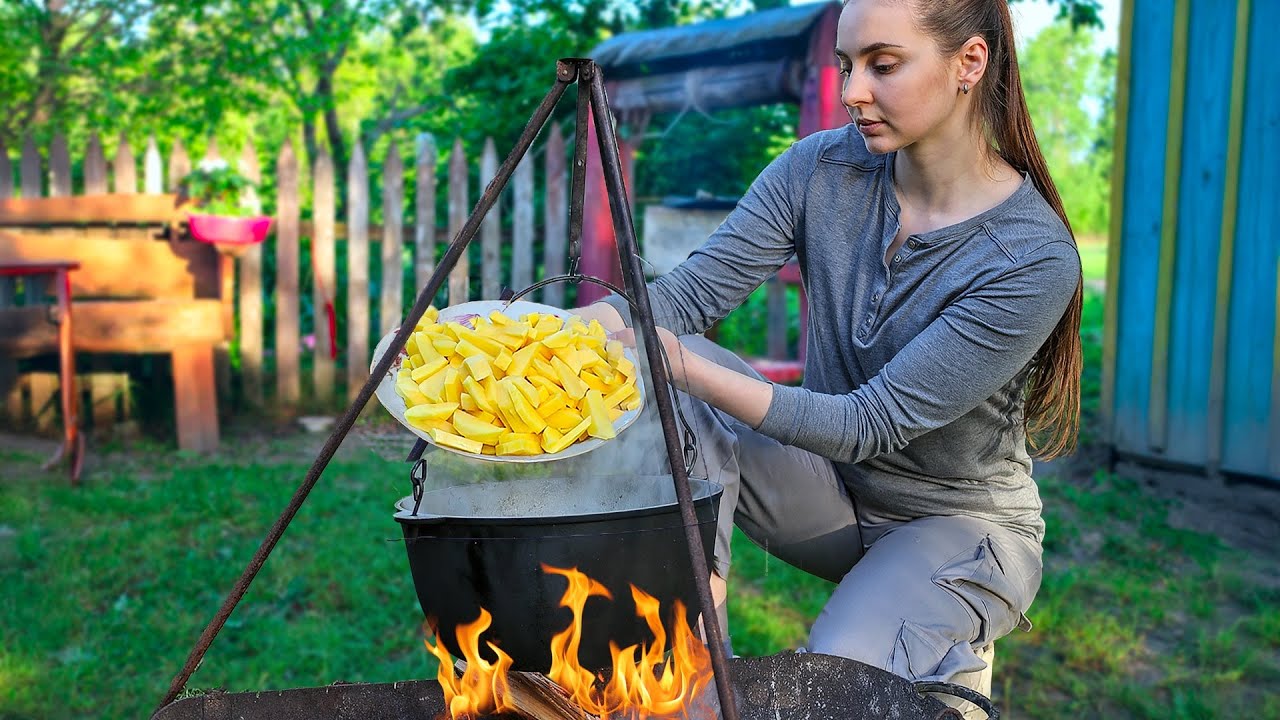 Ukrainian girl cooks Ukrainian Green Borscht in the village, yard work ...