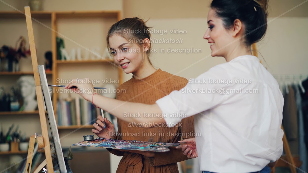 Experienced art teacher is teaching her student to paint with oil ...