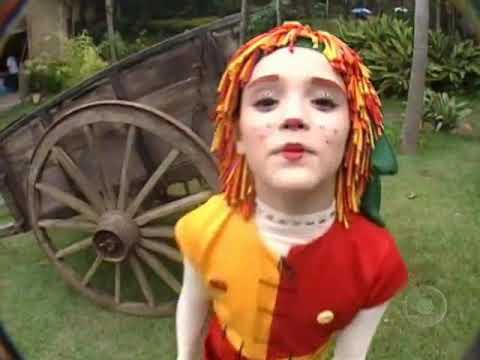 Emília (Isabelle Drummond) manda beijo pras câmeras em 2005 no Globo Repórter na Rede Globo