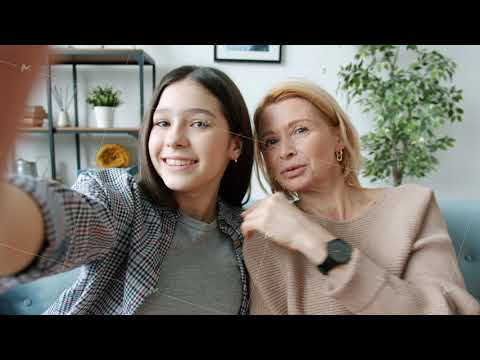 Portrait of mother and daughter looking at camera and talking through video call at home