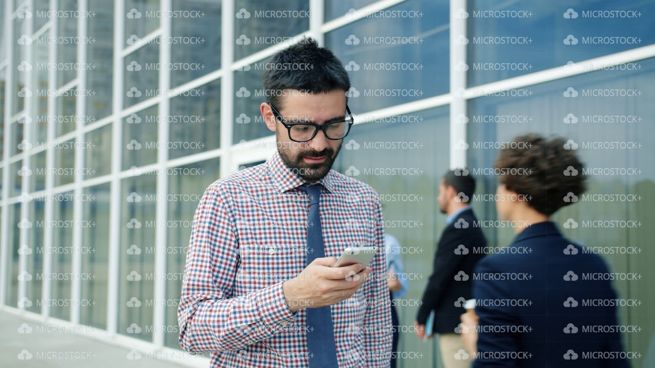 Cheerful office worker texting using smartphone smiling outdoors in ...