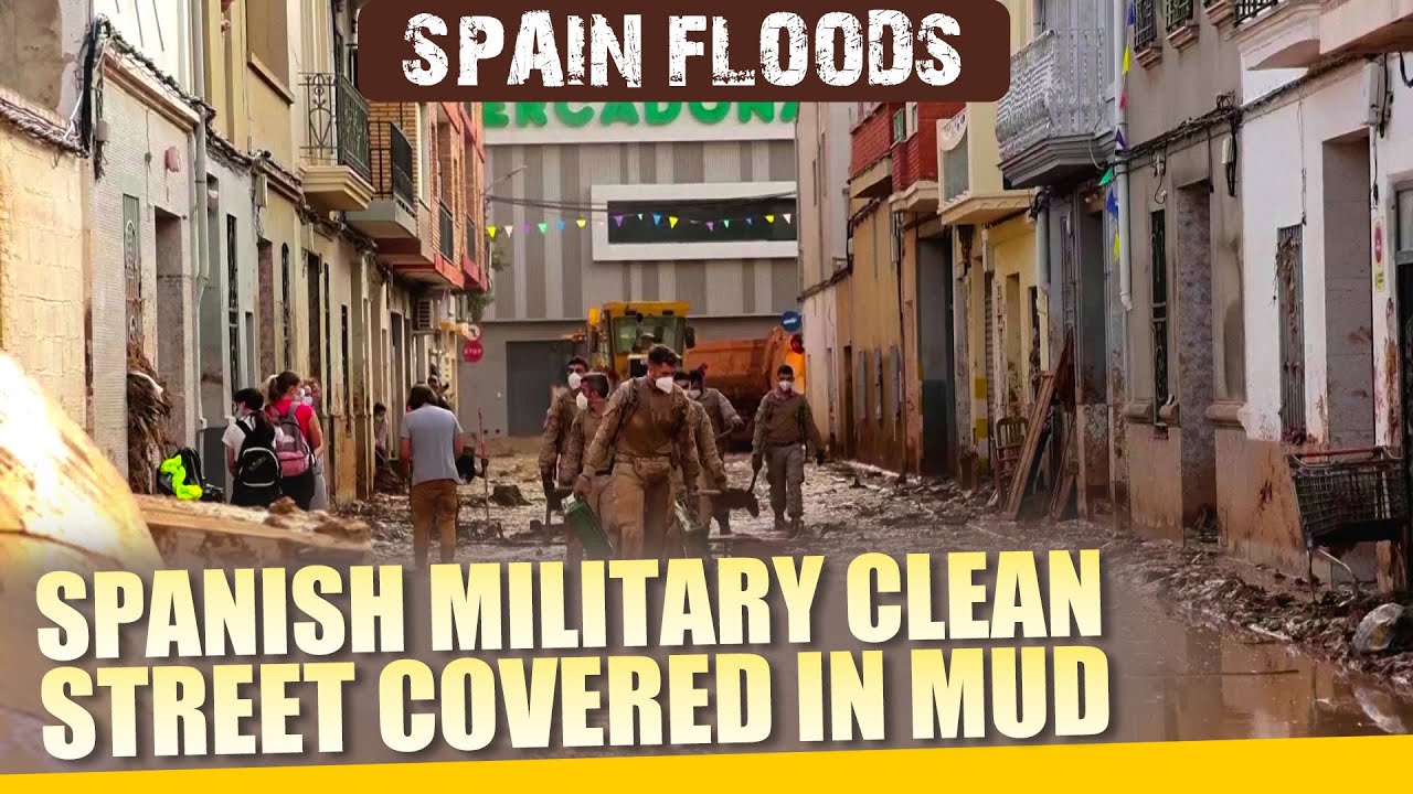Spanish military clean street covered in mud and debris, in the ...