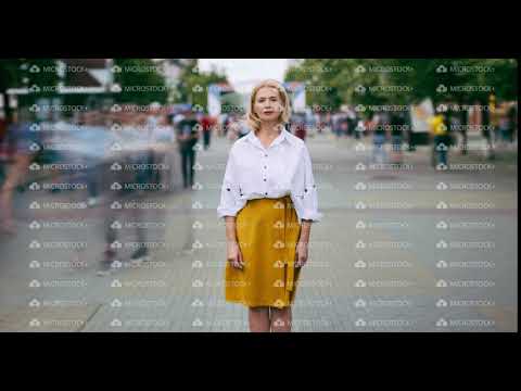 Zoom out time lapse of pretty mature woman looking at camera standing in street