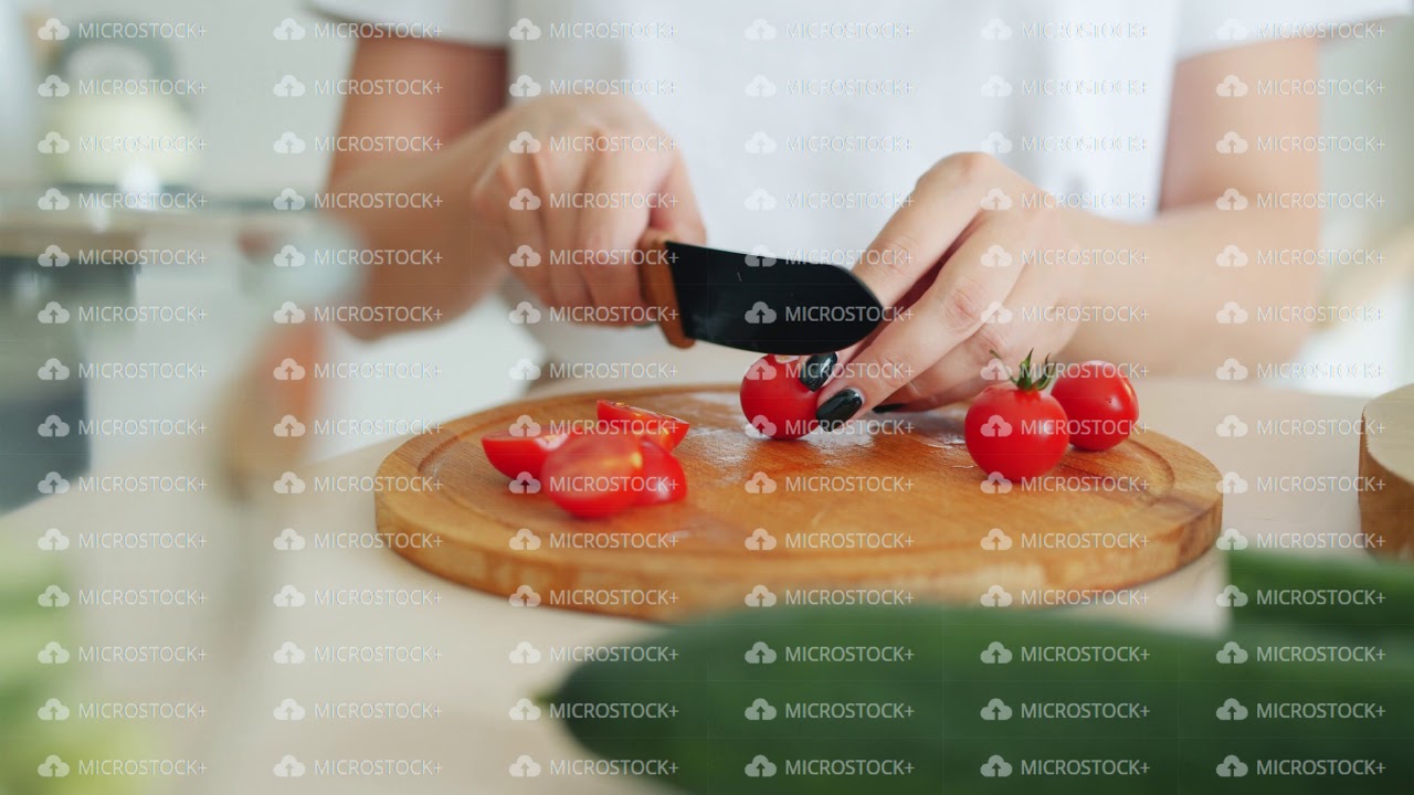 Close-up slow motion of female hand chopping tomatoes of wooden cutting ...