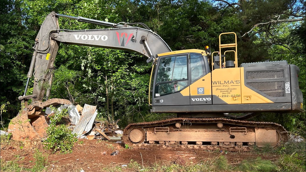 Excavator cleaning up demolition job and lowboy trailer moving tractor ...