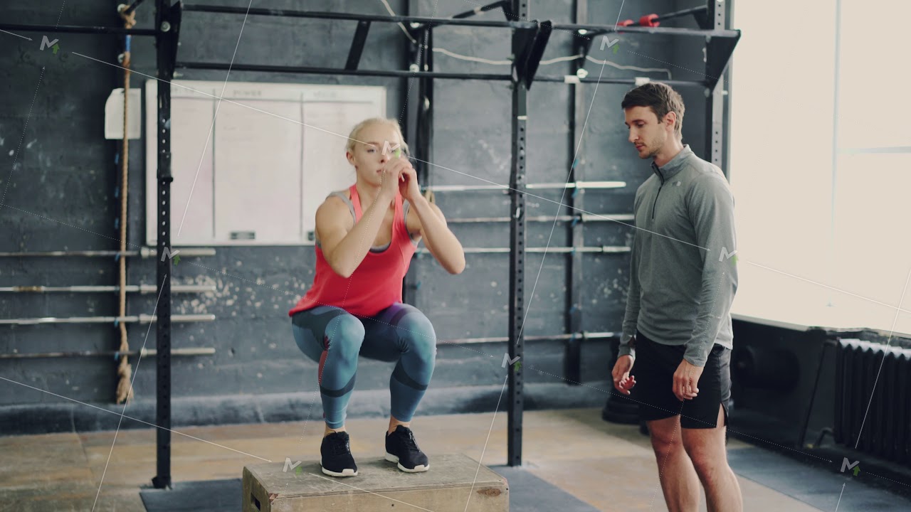 Fit young woman concentrated on wooden box jumps during crossfit ...