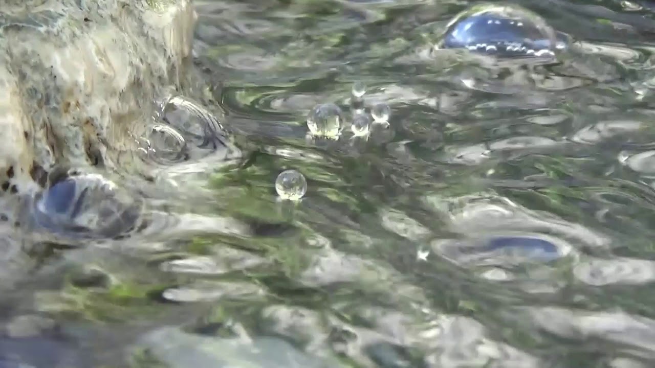 Druppels water drijvend op water met een film van lucht tussen water en ...