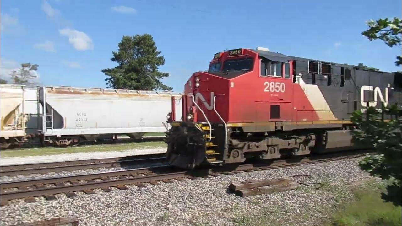 CN 2850, 3924 dashing a Westbound freight train with BN hoppers, BC flat cars past Harborlite ...