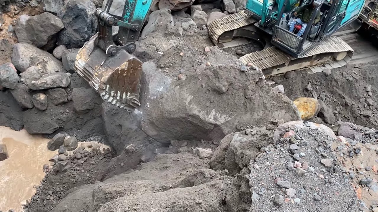 Heavy equipment works in sand mining, breaking down large rocks - YouTube