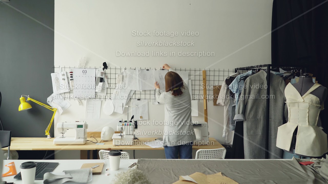 Back view of creative female tailor taking sketches from tailoring desk ...
