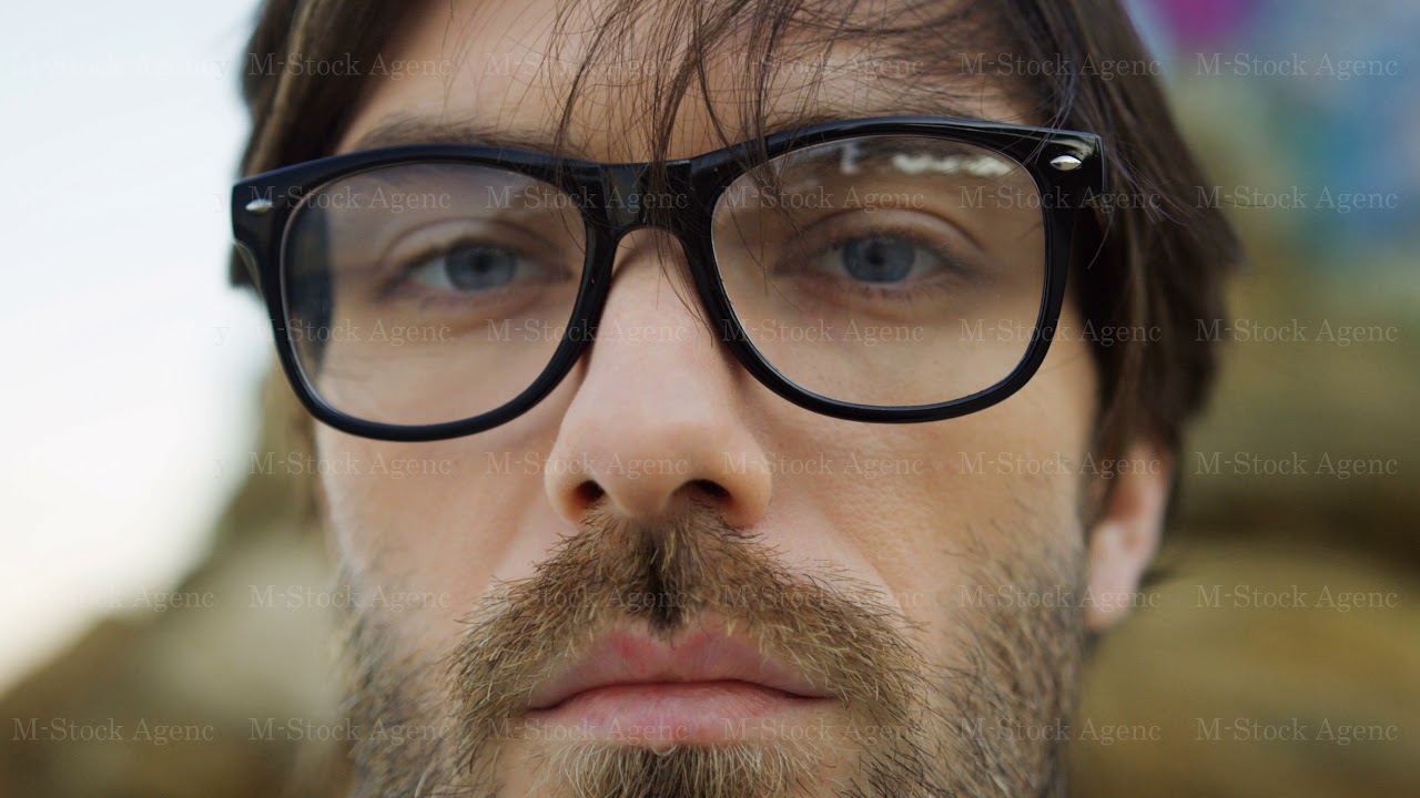Close up of male attractive face with beard and in glasses. Thoughtful ...