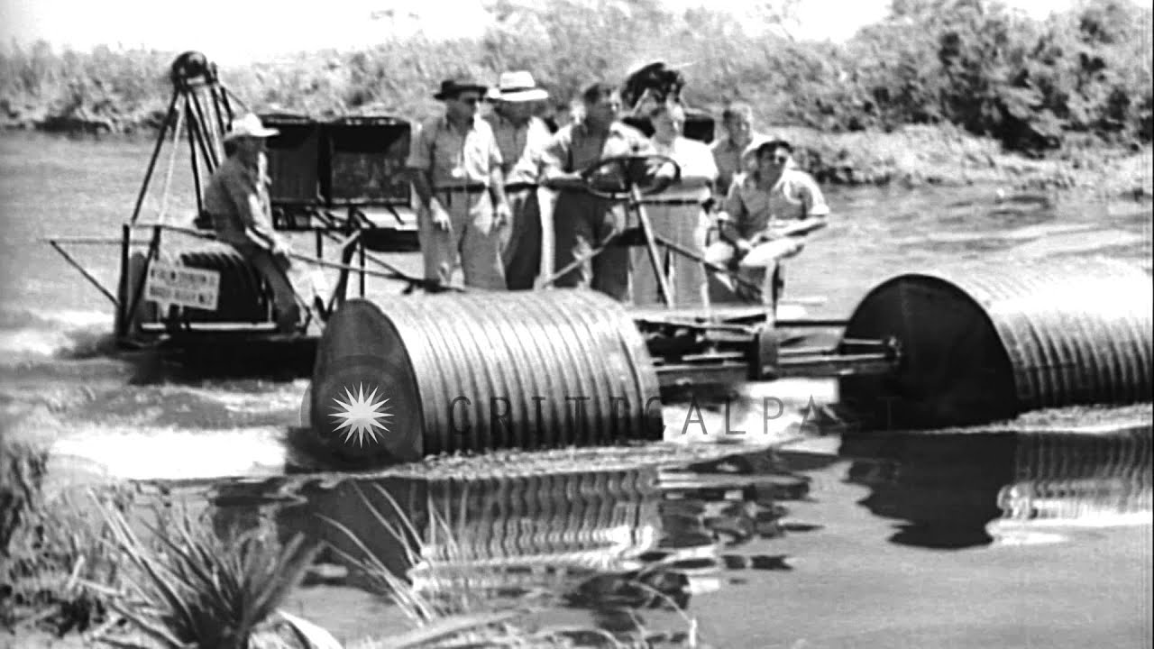 Men drive a swamp mobile built with propellers and drum wheels across a ...