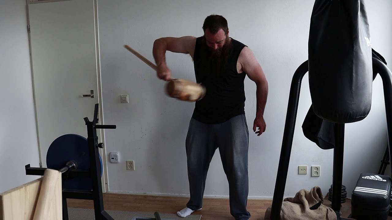 Hitting the abdominal muscles with a large wooden sledgehammer - YouTube